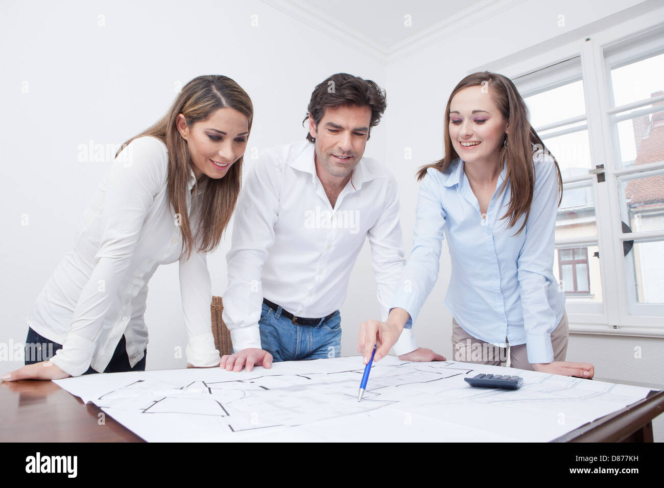 Germany, Bavaria, Munich, Man and women discussing blueprint, smiling ...