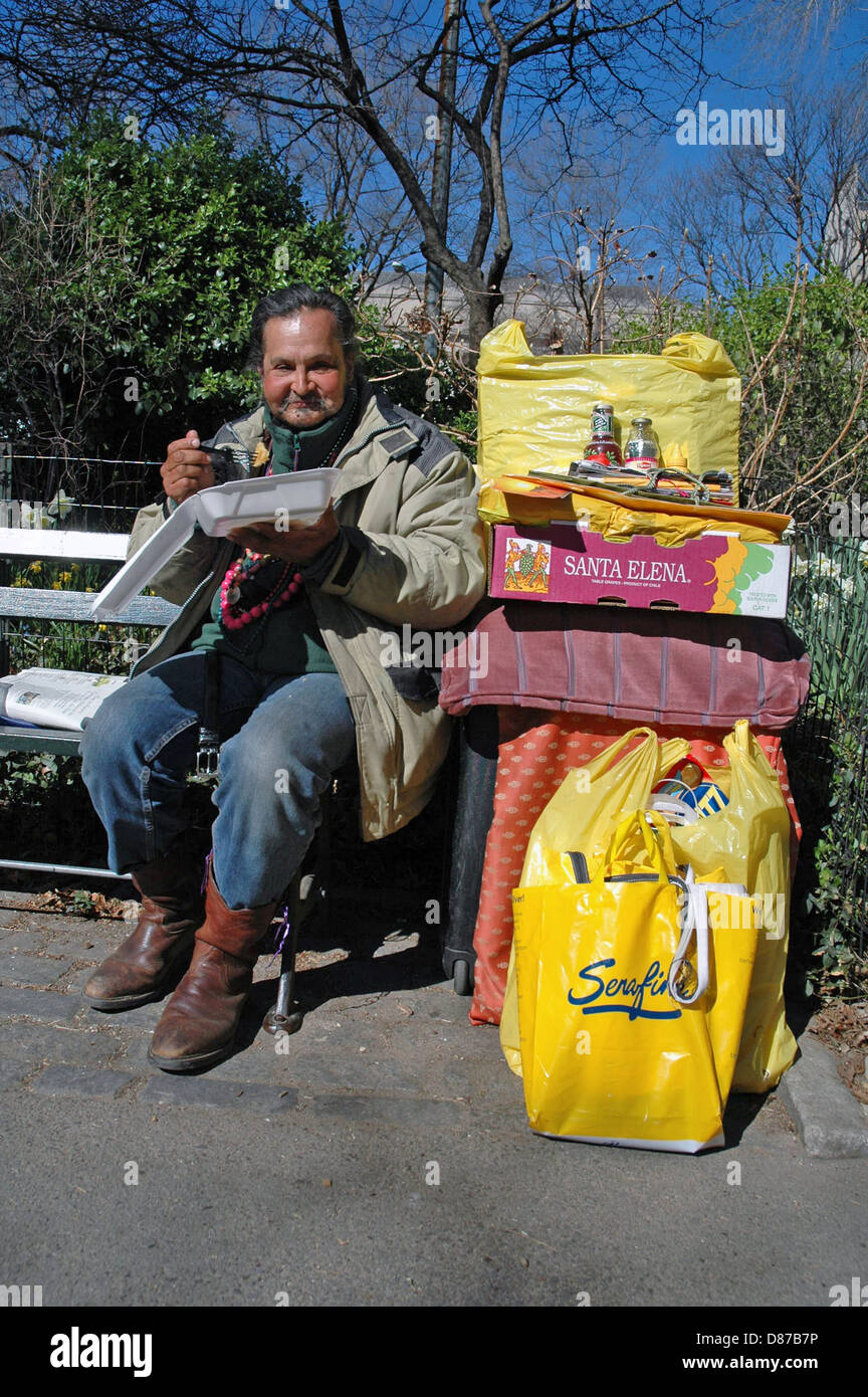 Homeless man in New york City sitting on bench eating takeaway meal ...