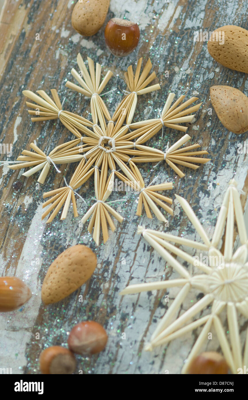 Christmas decoration with straw star, hazelnuts and almonds on table ...