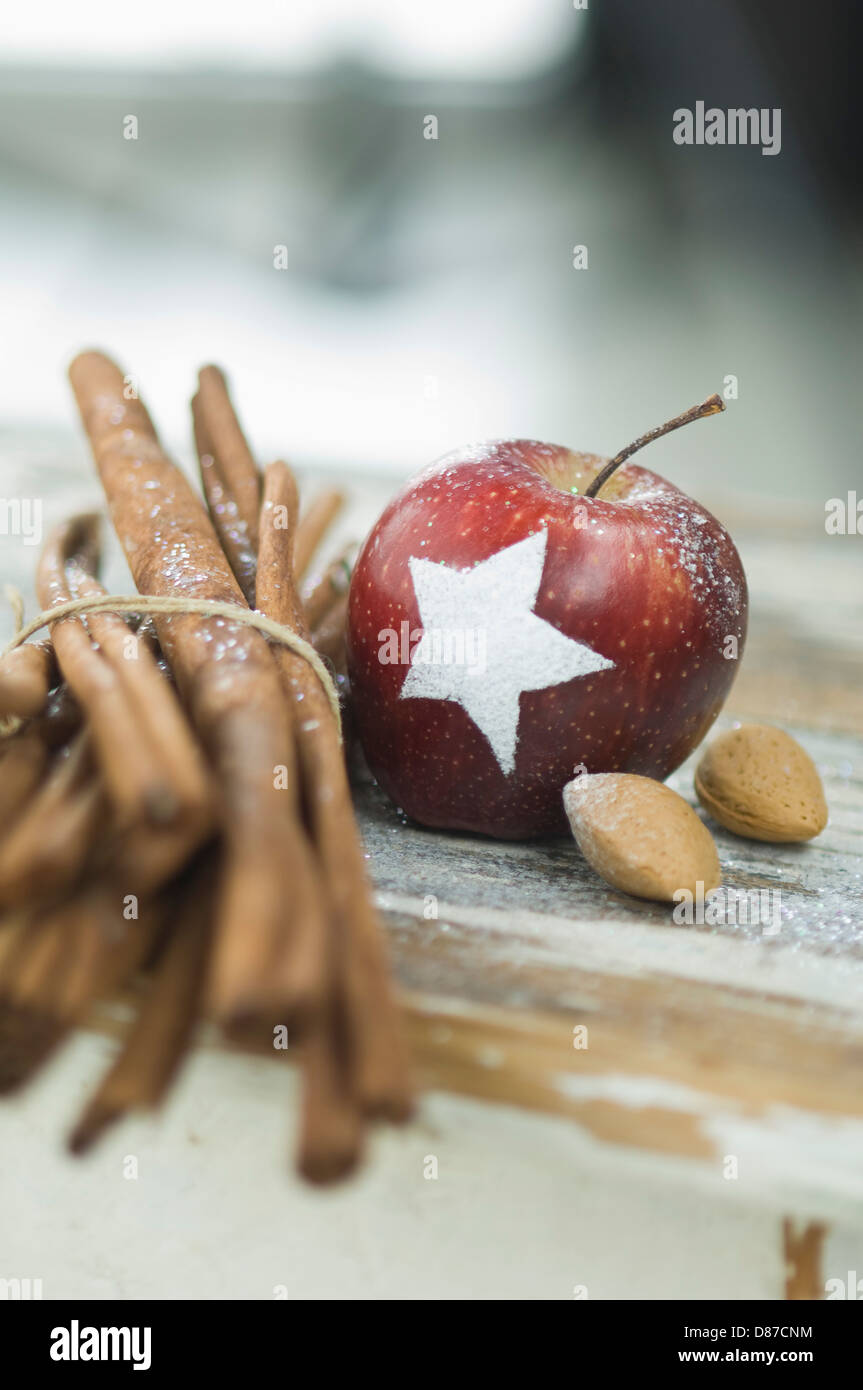 Christmas apple with snow star, cinnamon sticks and almonds on table ...