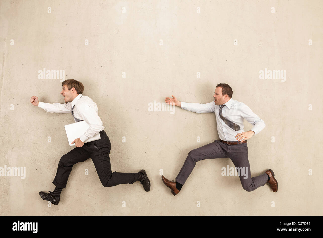 Businessmen chasing against beige background Stock Photo - Alamy