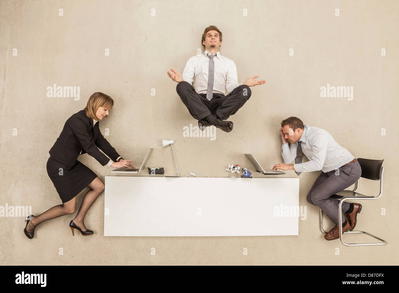 Businessman meditating above office desk while others working Stock ...