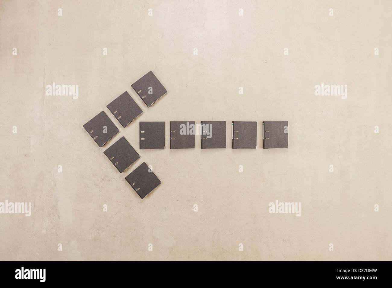 Files forming arrow sign on beige background Stock Photo - Alamy
