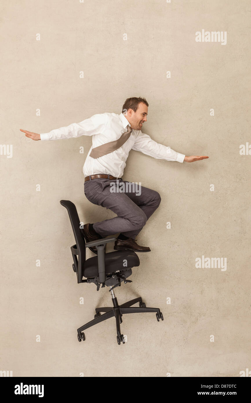 Businessman skating on office chair Stock Photo - Alamy