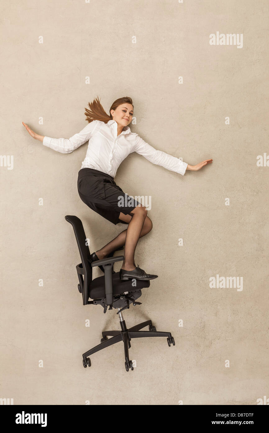 Businesswoman skating on office chair Stock Photo - Alamy