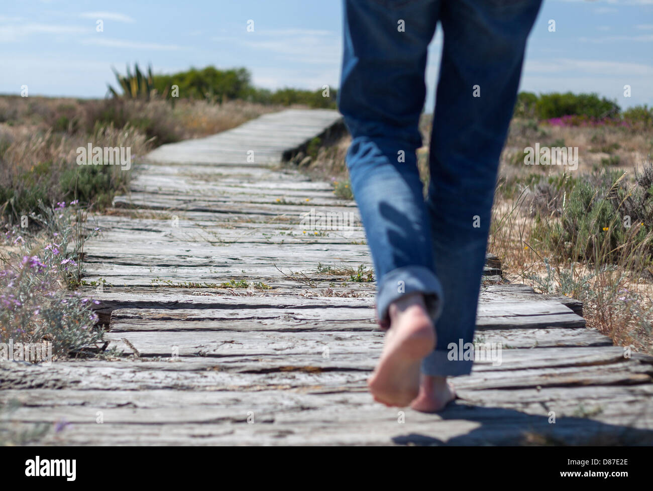 A woman walks barefoot on a wooden gangway in a desert island on a ...