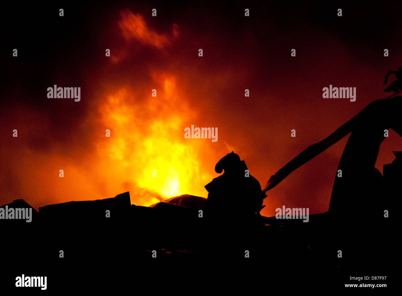 Silhouette of Firemen fighting a raging fire with huge flames of ...