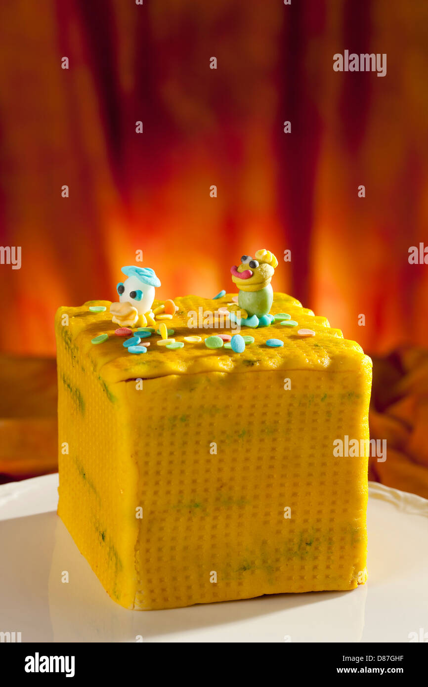 Cube of cake with yellow icing and figurines, close up Stock Photo - Alamy