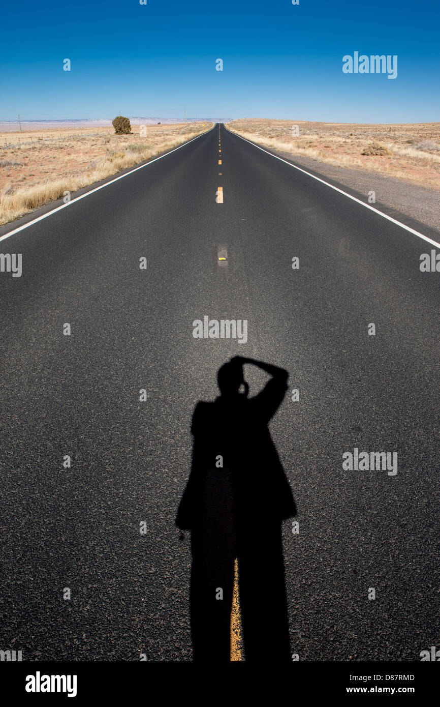 Photographers shadow on a long straight road Stock Photo - Alamy
