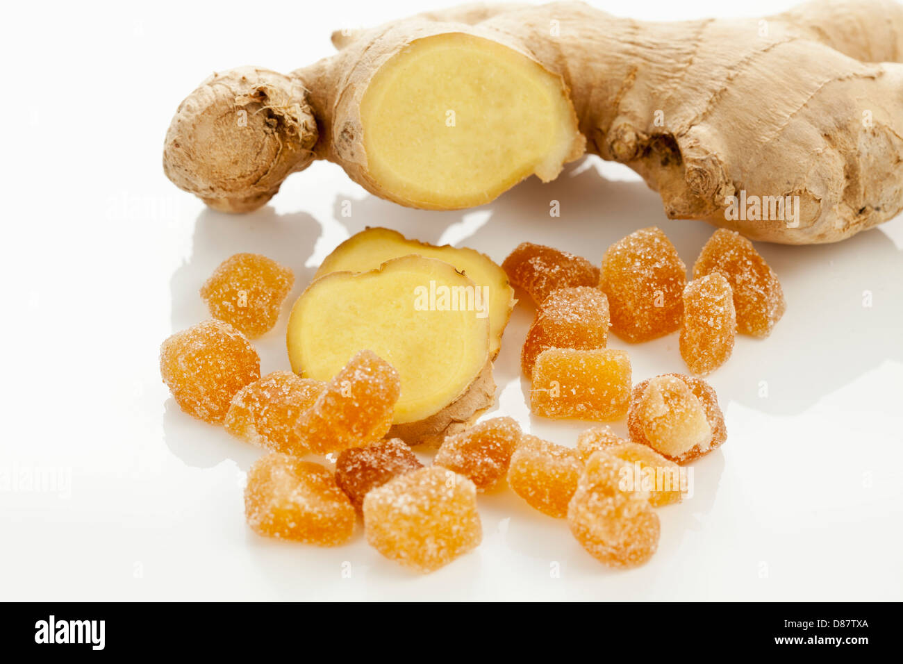 Sliced ginger and pieces of candied ginger on white background, close ...