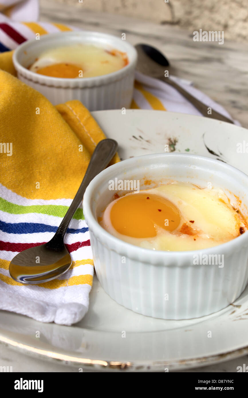 Egg in ramekin with tomato souce and chorizo not cooked. Vertical photo ...