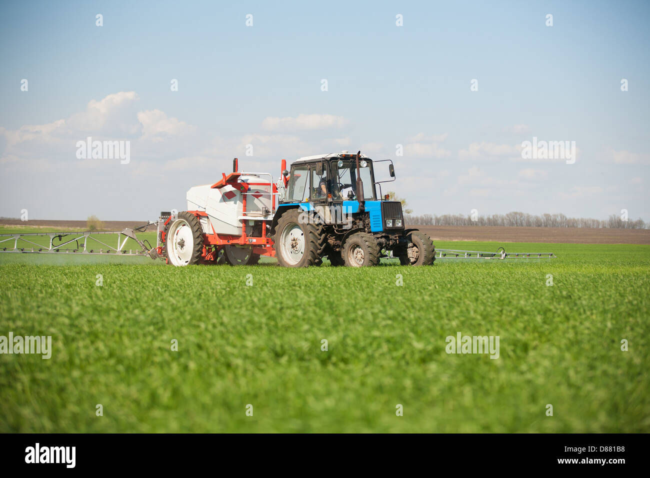 Tractor spraying a fresh green field on a farm Stock Photo - Alamy
