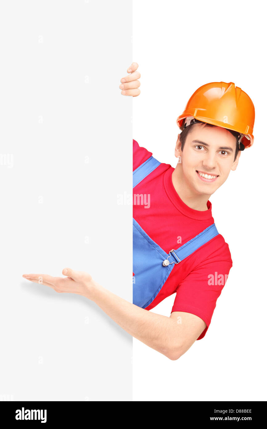Young construction worker with helmet posing behind a blank panel ...