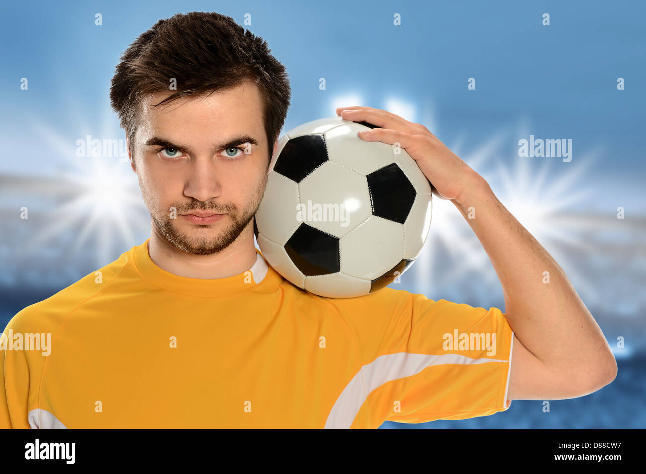 Portrait of young soccer player holding ball with stadium in background ...