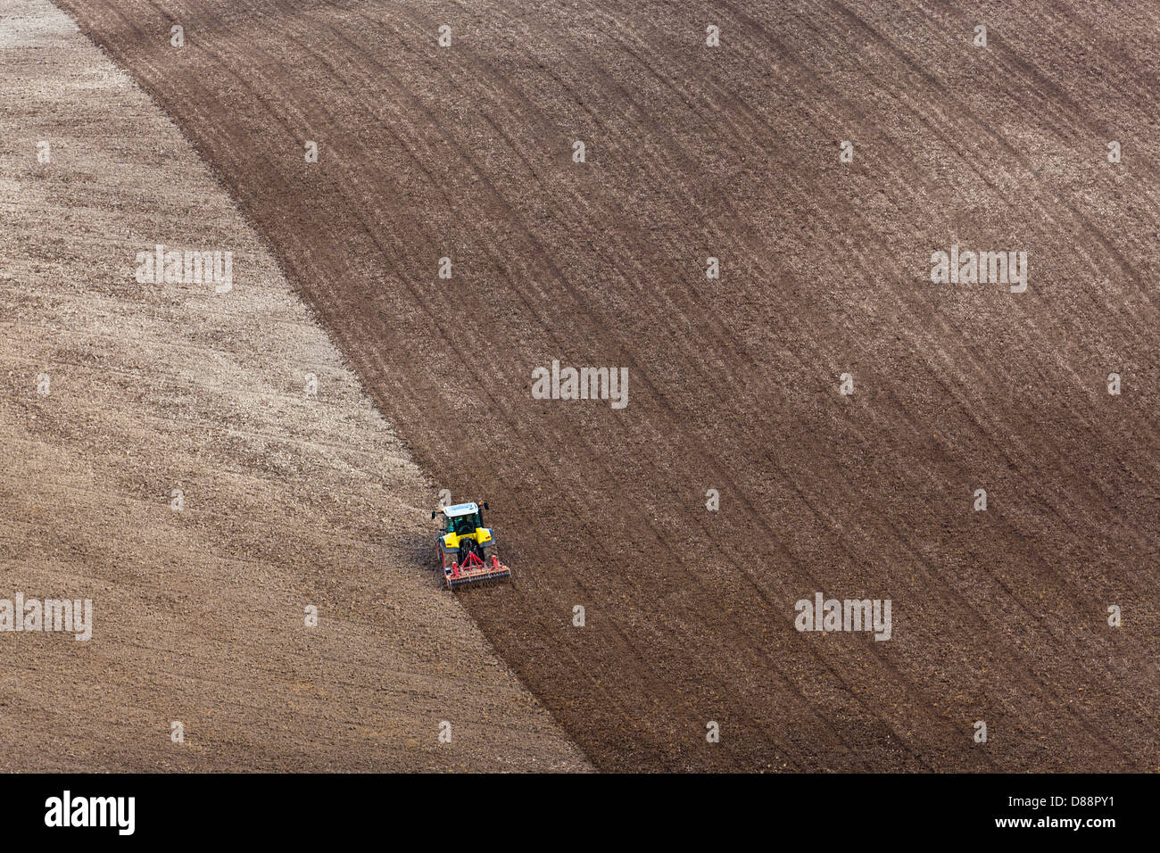 A tractor raking a ploughed field in preperation for sowing the years ...