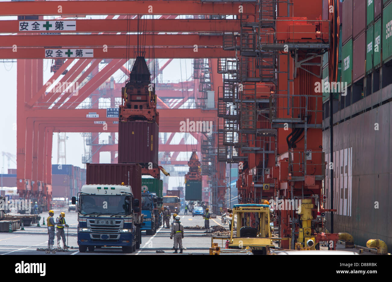 Tokyo, Japan - Workers manage containers from ship docked in cargo area ...