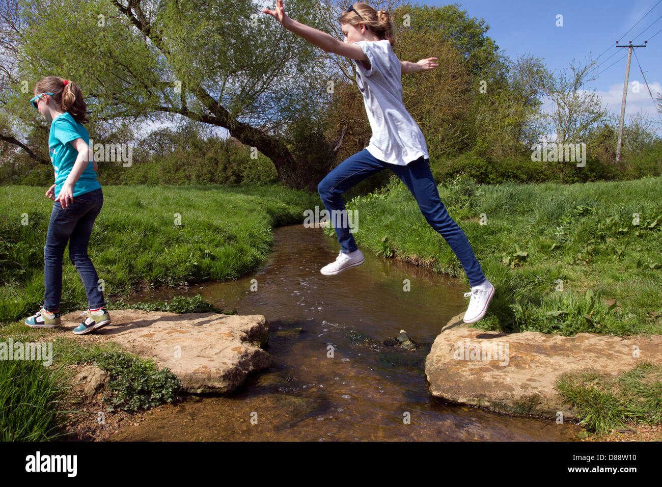 young girl jumping over a stream Stock Photo - Alamy
