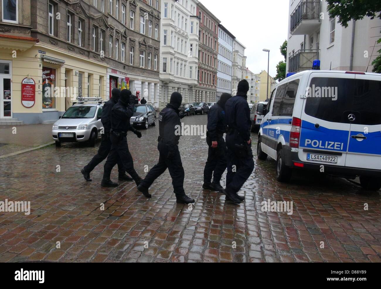 Masked police officers cross a street before searching a house during a ...