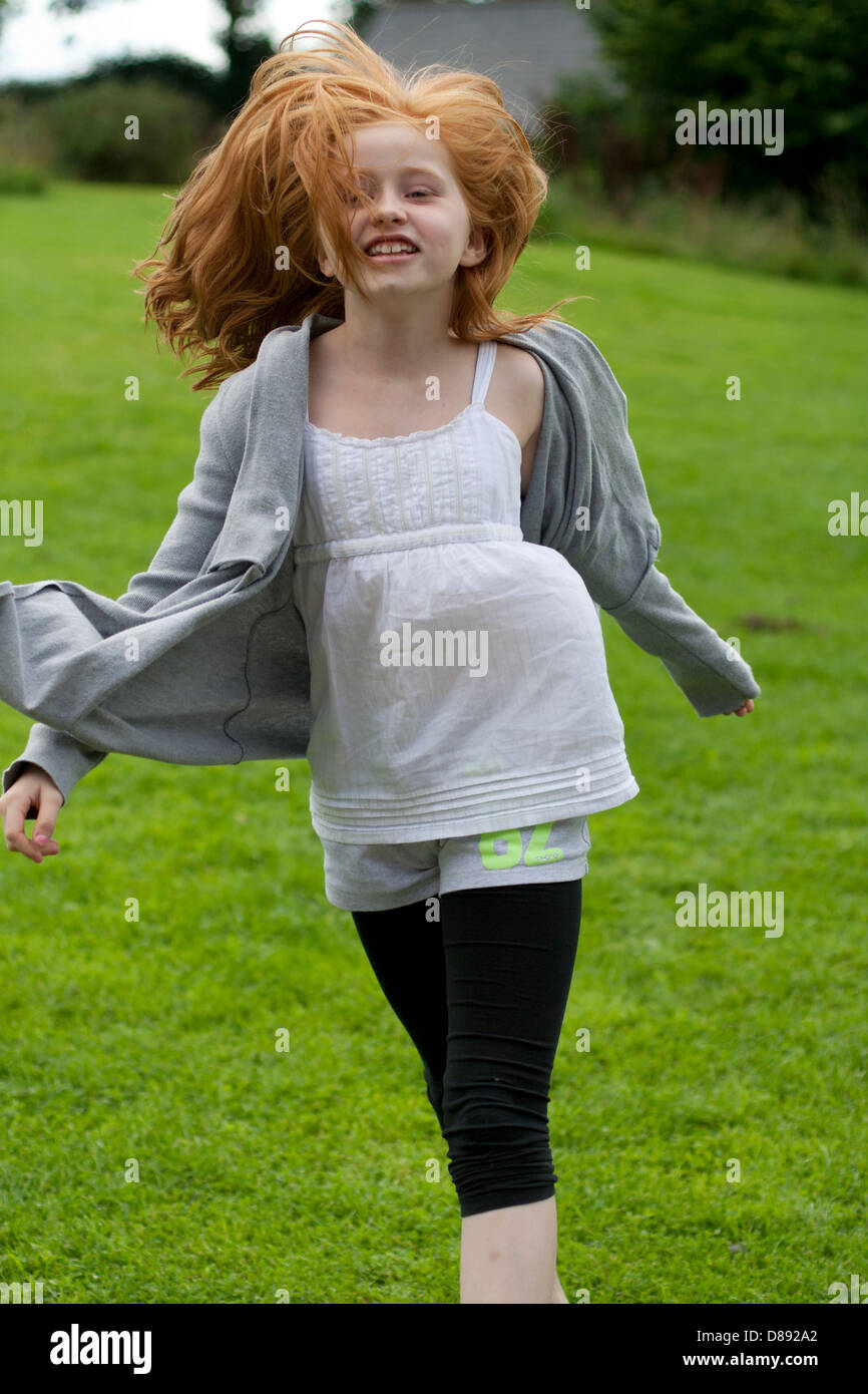 Little girl skipping happily down a hill Stock Photo - Alamy