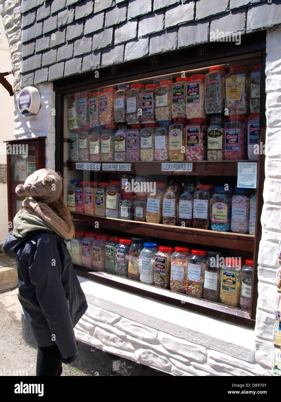 Young woman looking in the window of a traditional sweet shop, Polperro ...