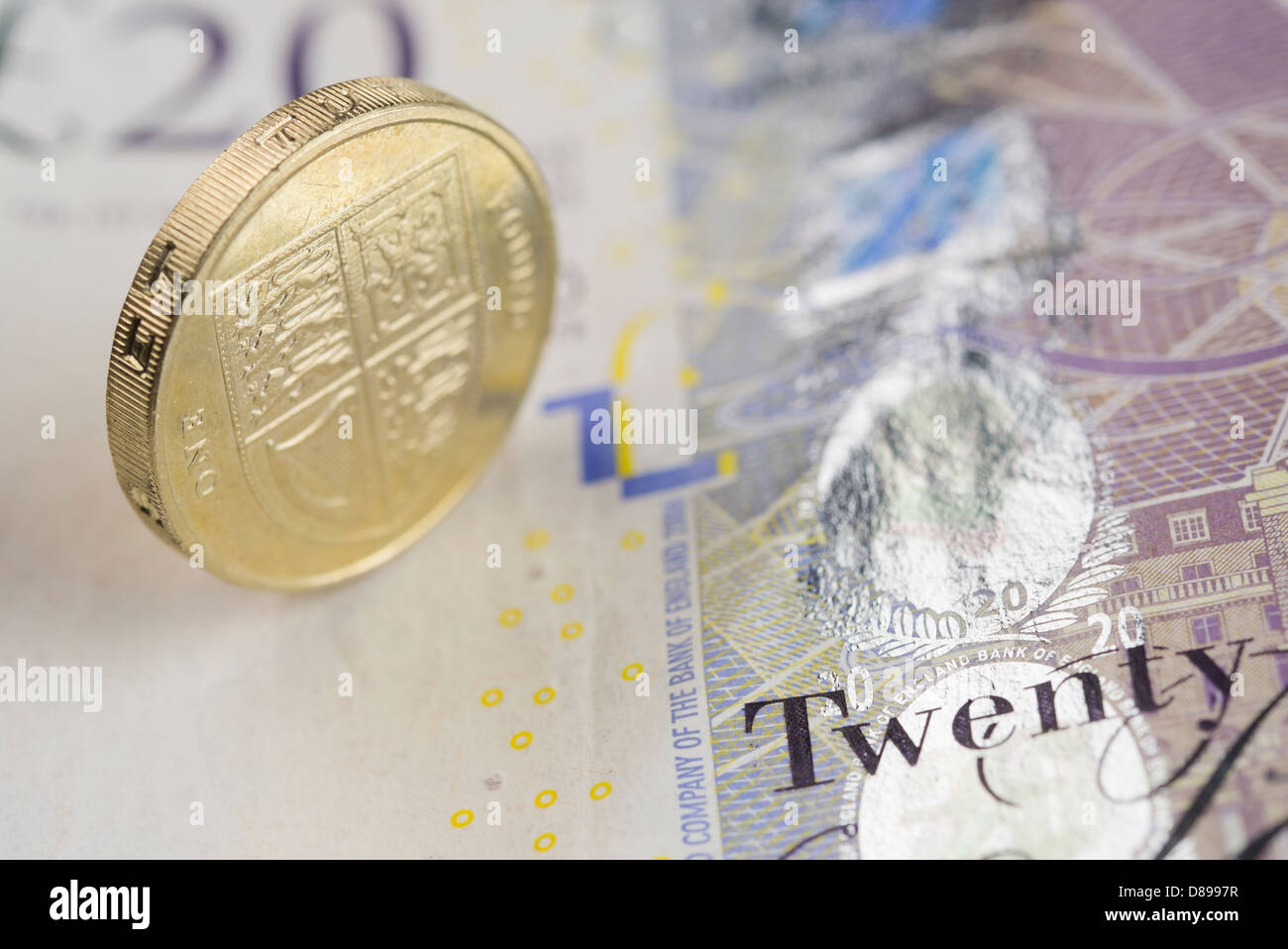 A pound coin standing upright on a twenty pound note Stock Photo - Alamy