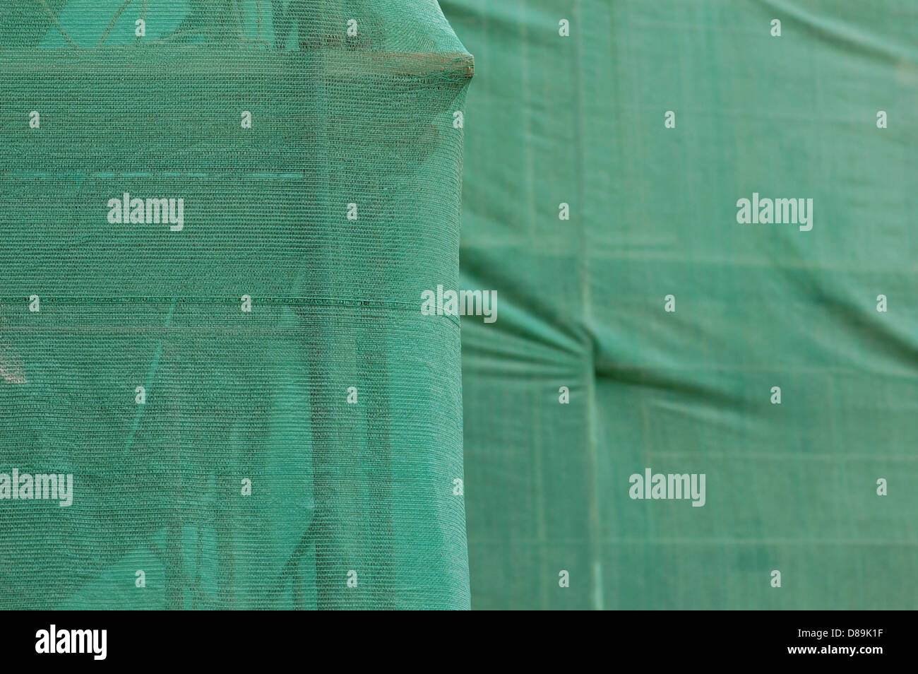 Scaffold under green debris netting at construction site. Abstract ...