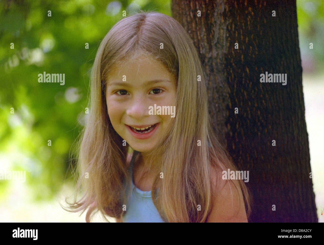 Cute blond girl by tree Stock Photo - Alamy