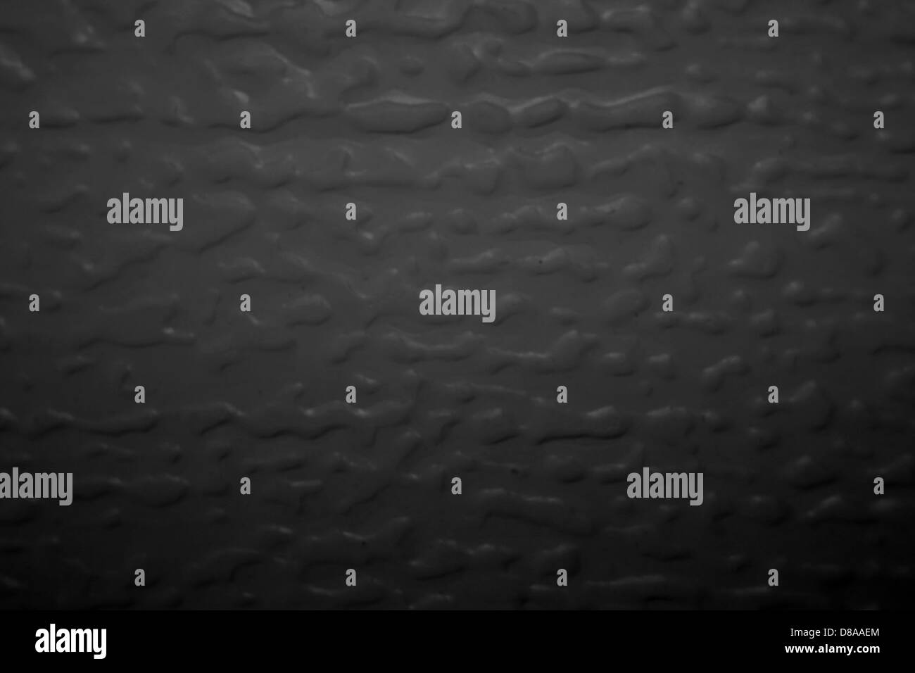 This image shows a close-up of a black plastic surface with a bumpy ...