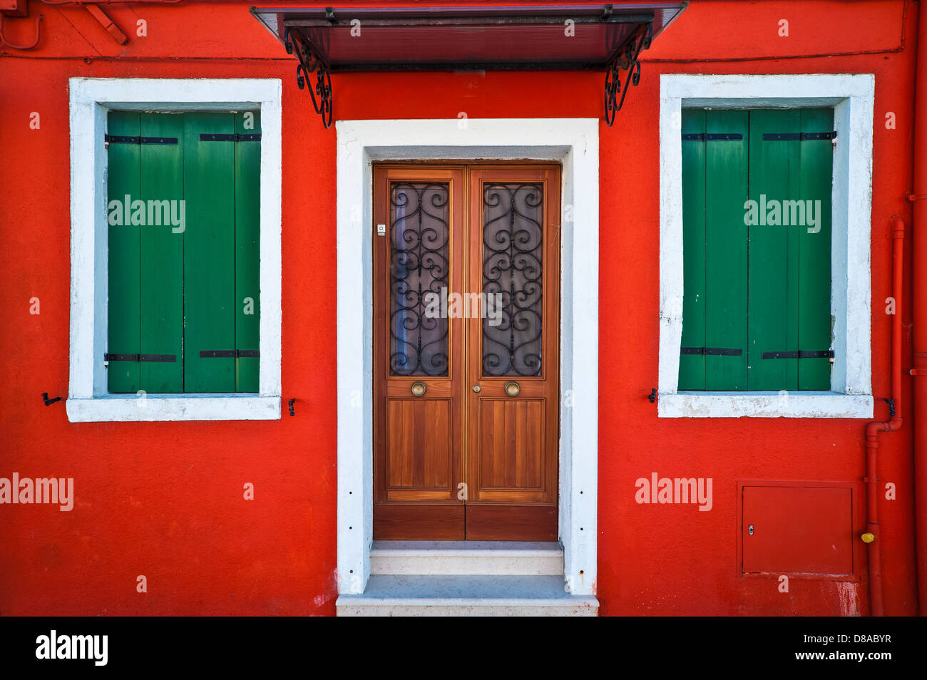 Front of a red house with green shuttered windows in Burano, Italy ...