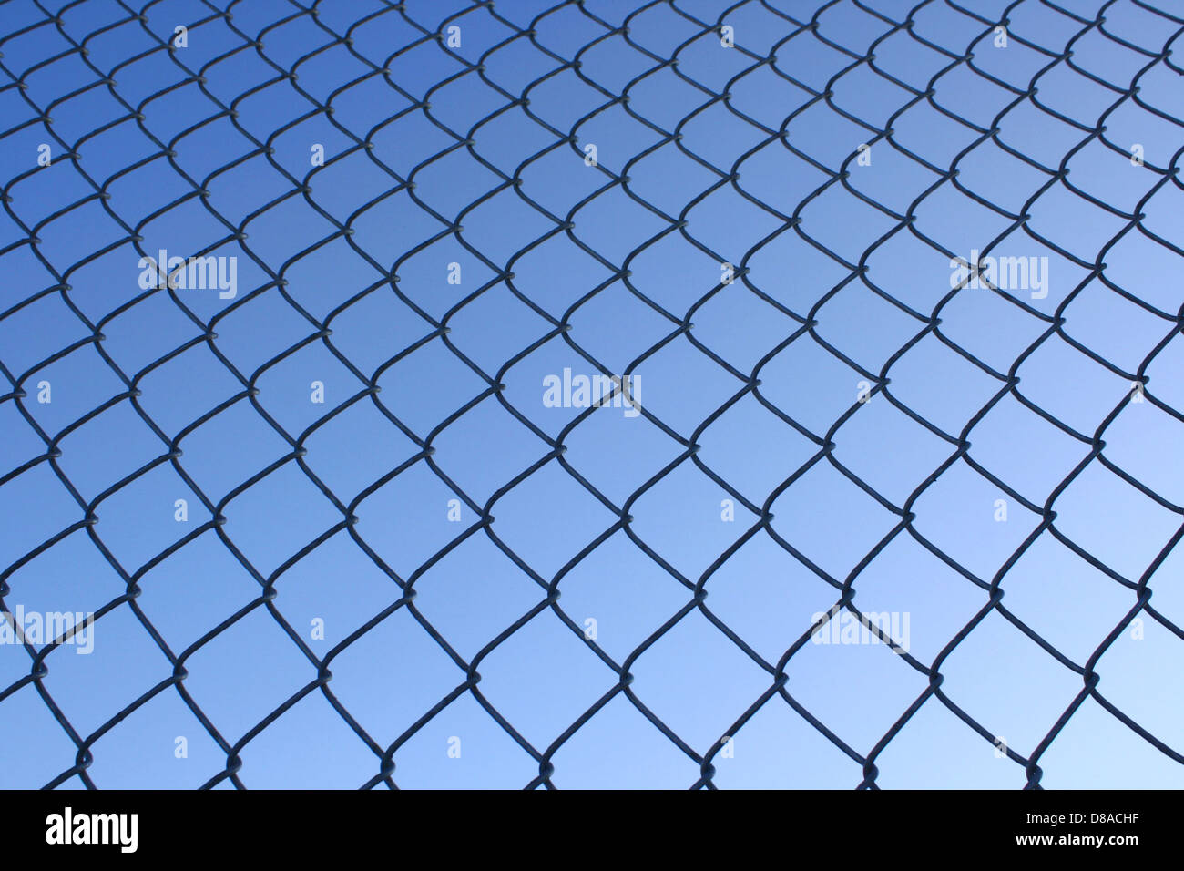 A close-up of a chain link fence shows its interwoven metal wires ...