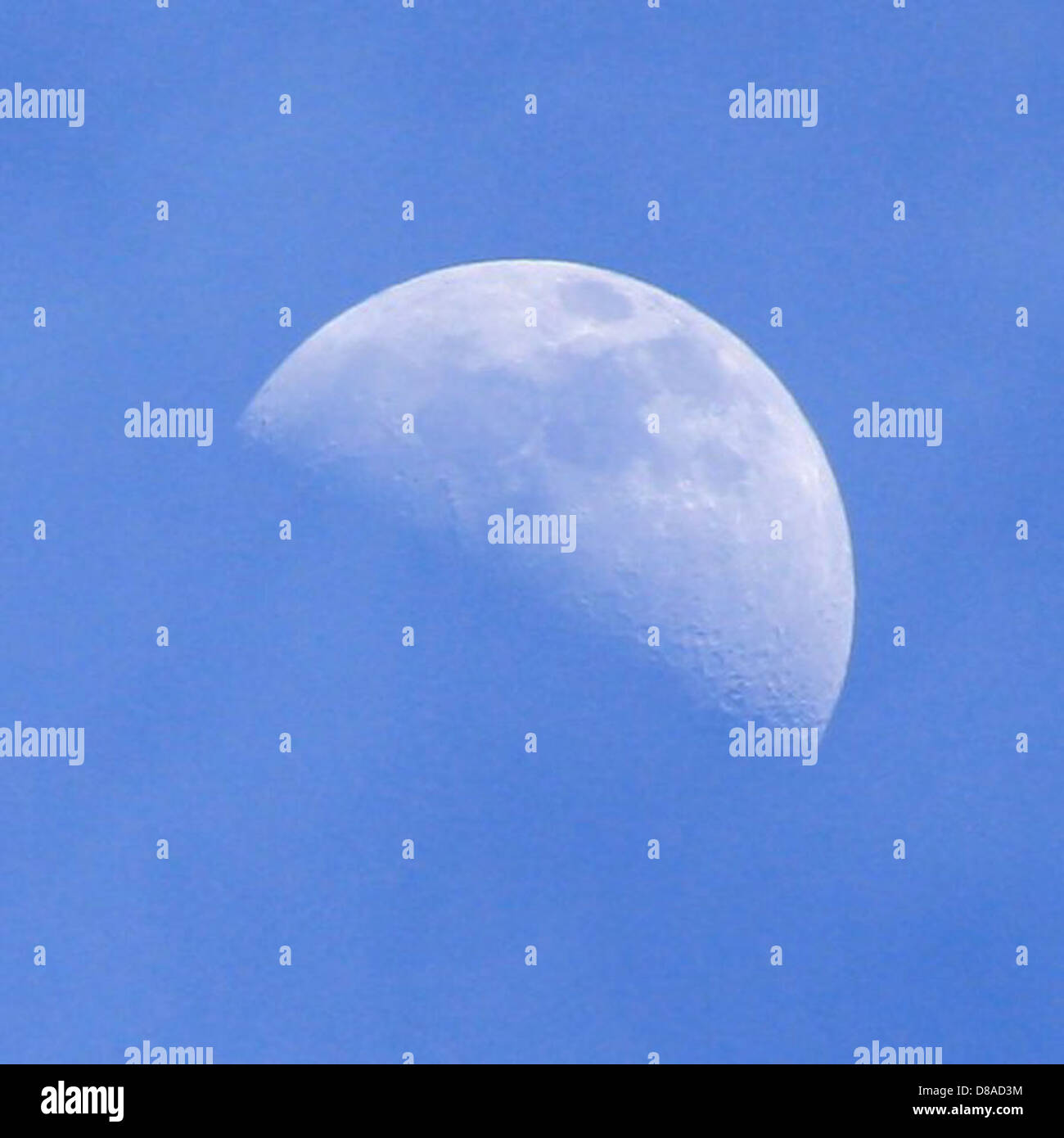 A photo of the moon visible in the daytime sky. The moon appears ...
