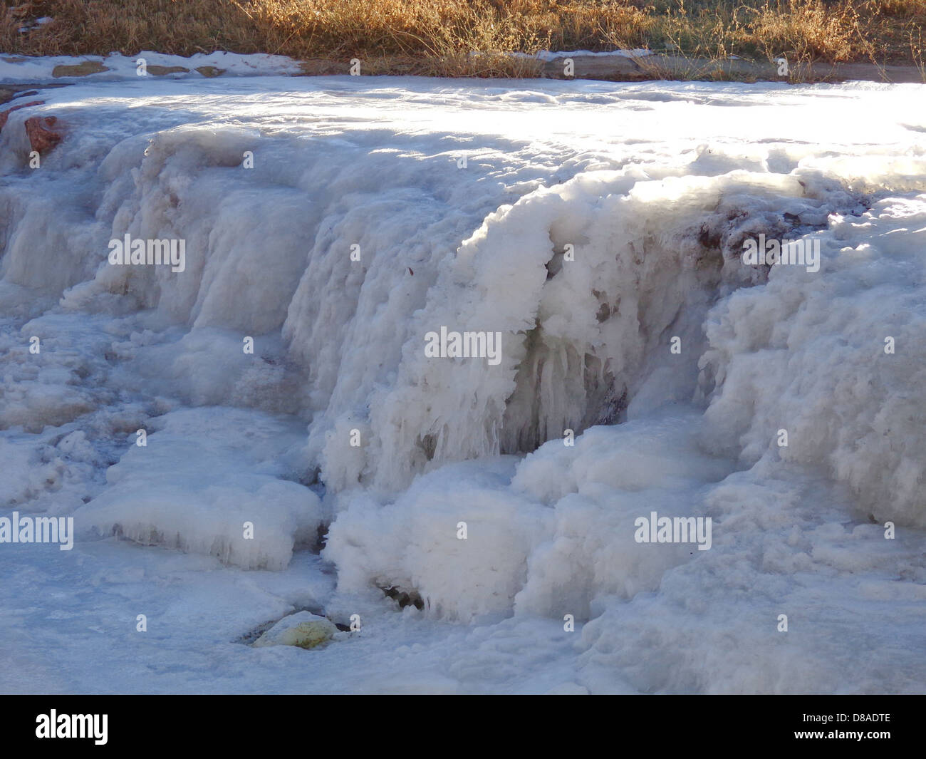 A frozen waterfall cascading over rocks along a winter river. The icy ...