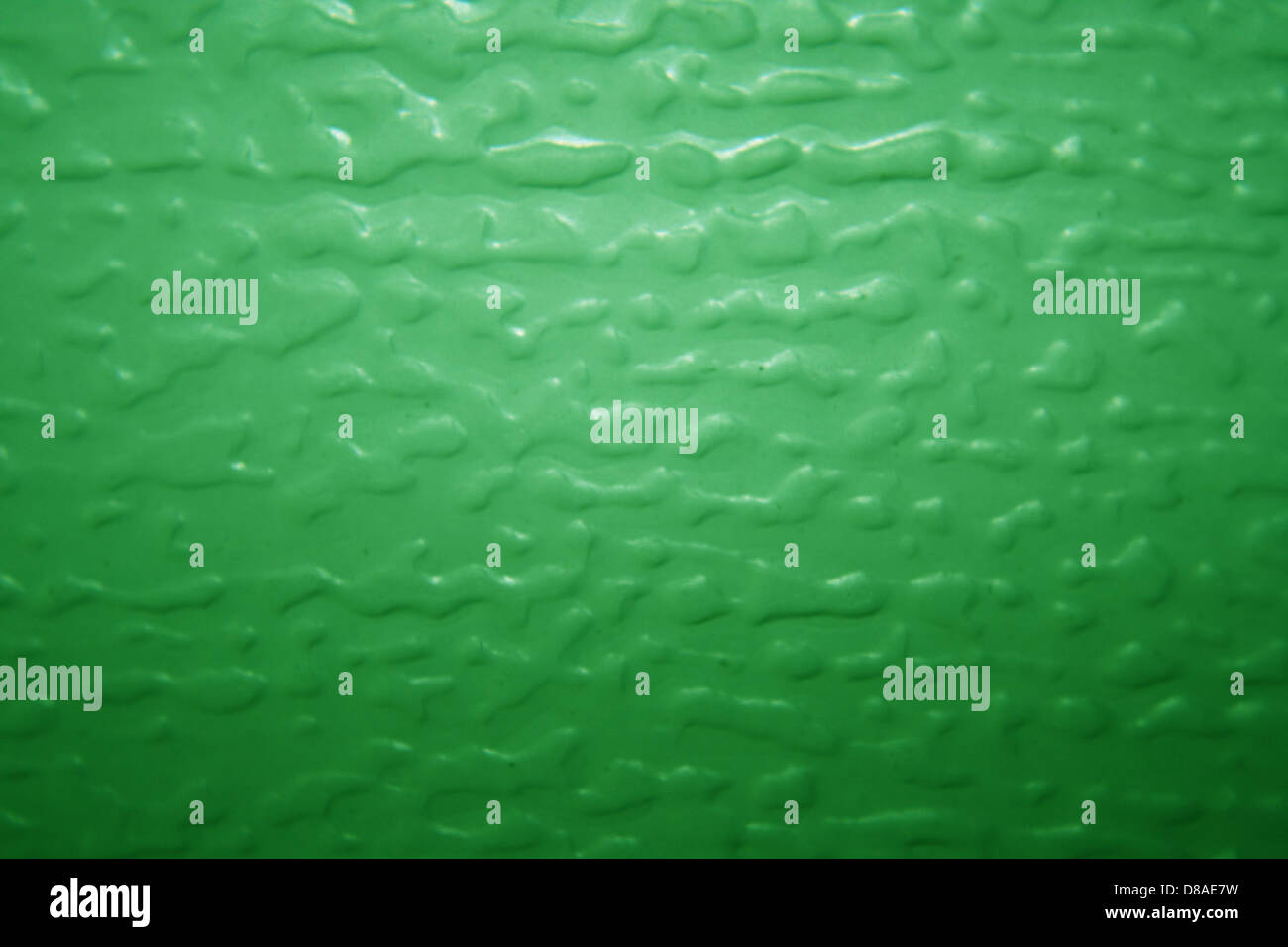 This image shows a green plastic surface with a bumpy texture. The ...
