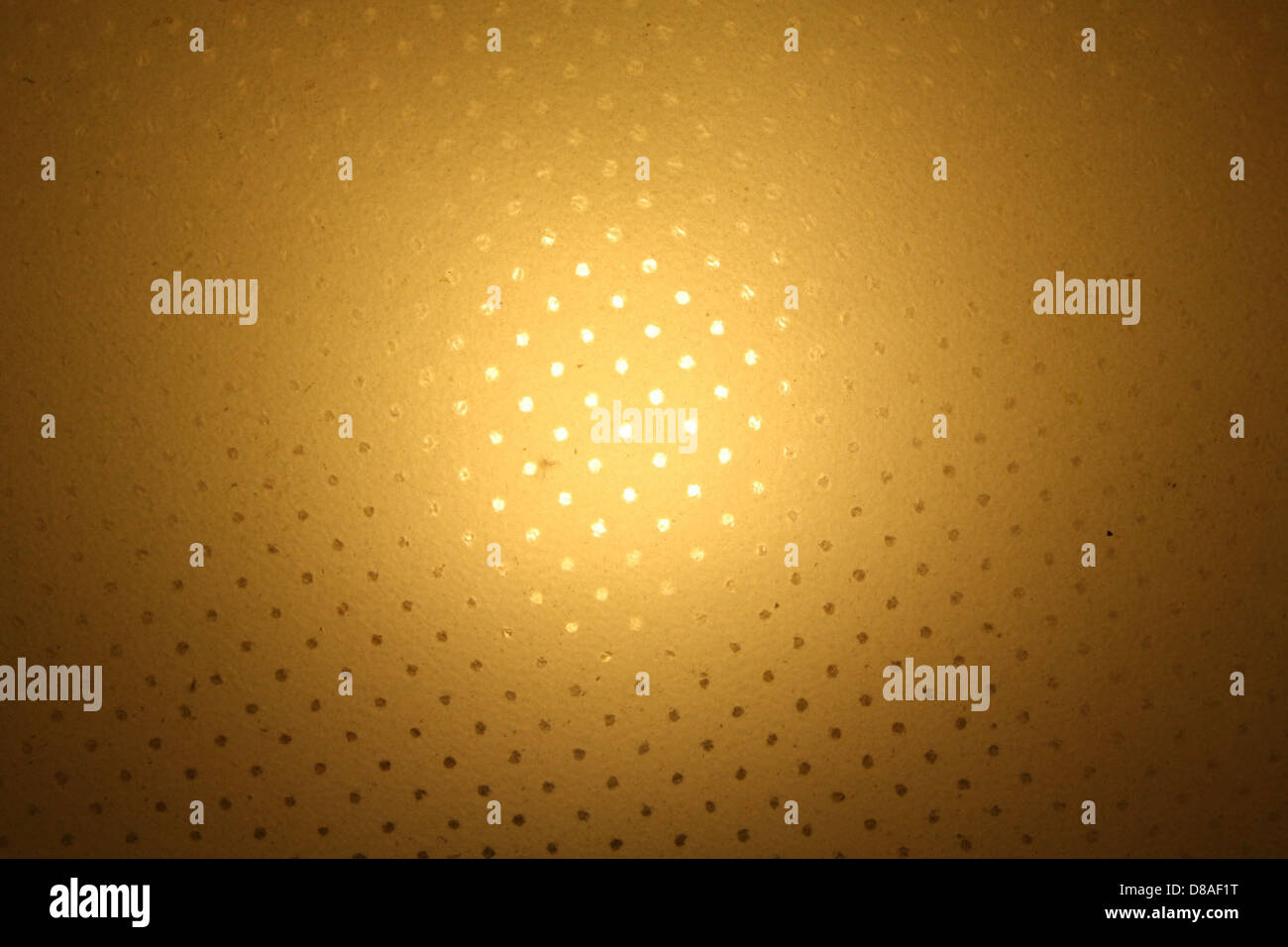 The light passing through a glass shade with small holes creates a ...