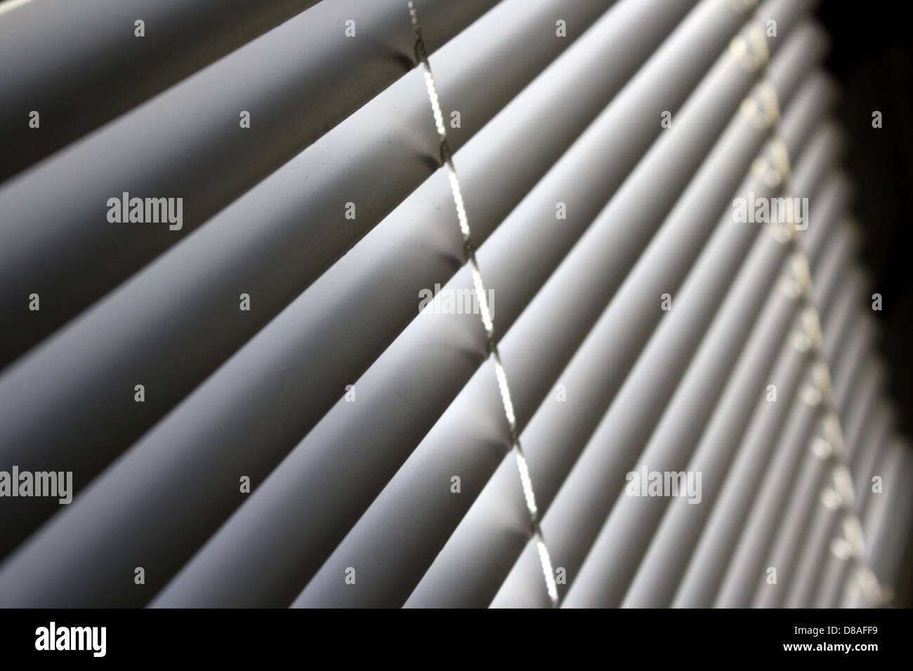 A close-up view of a mini blind window shade, with vertical slats that ...