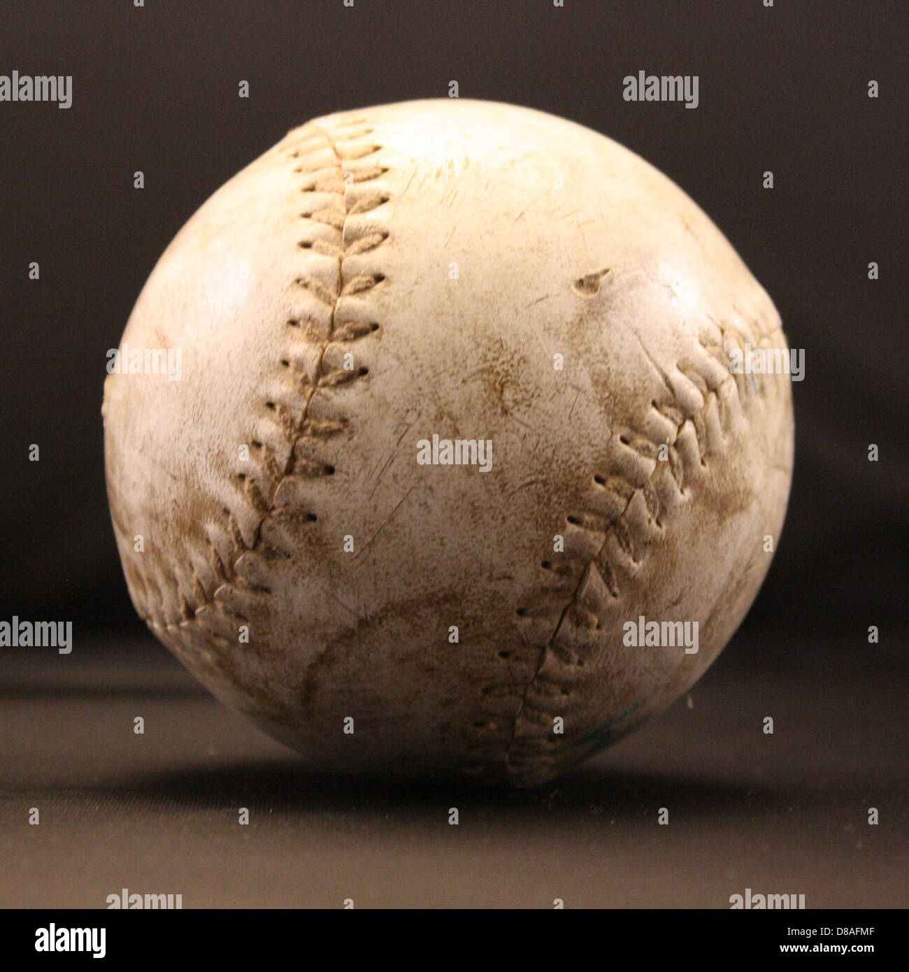 An old, worn-out softball is shown, its surface weathered and scuffed ...