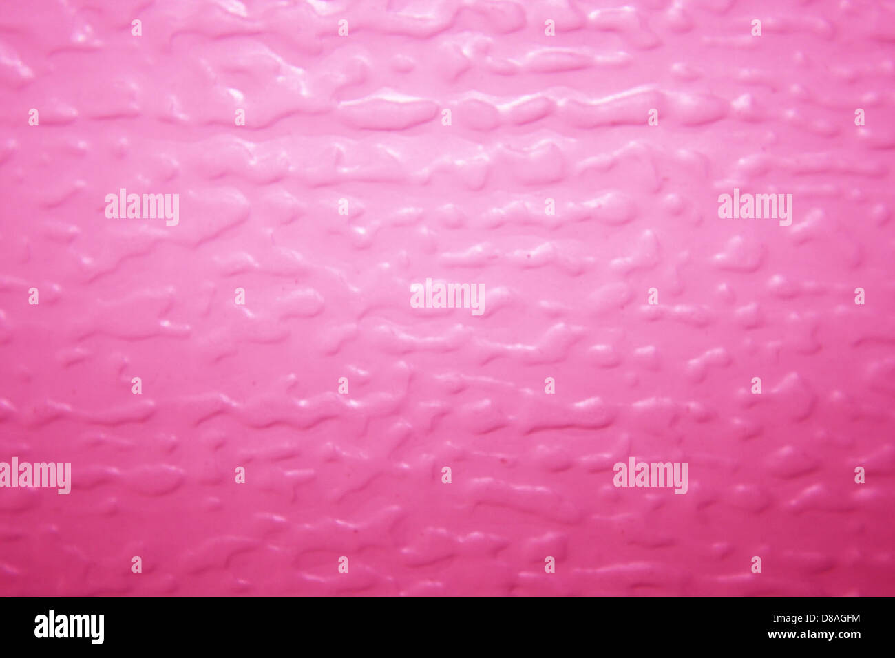 A close-up of pink plastic with a bumpy texture. The texture is ...