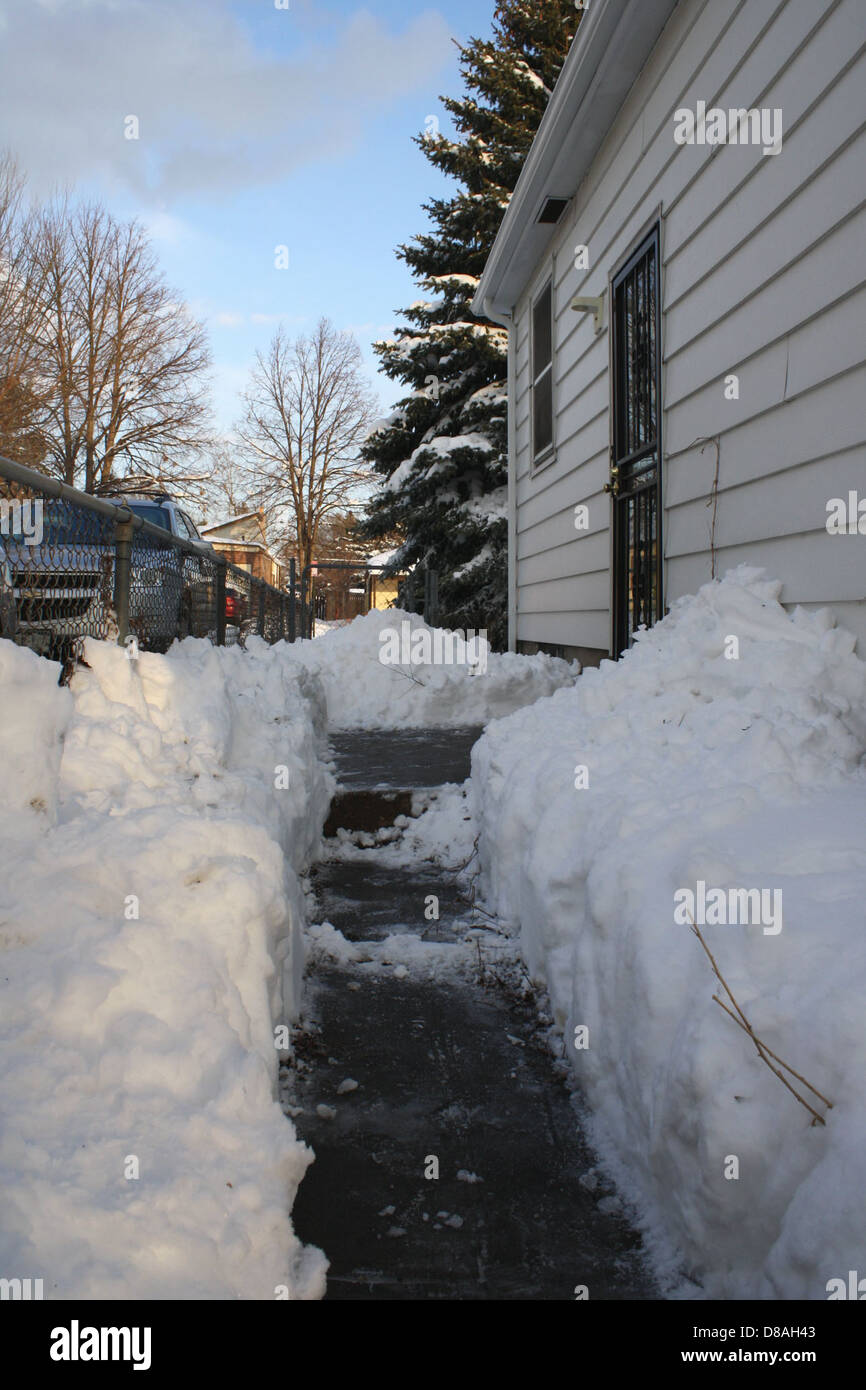 A sidewalk cleared of deep snow, with a clear path carved through the ...