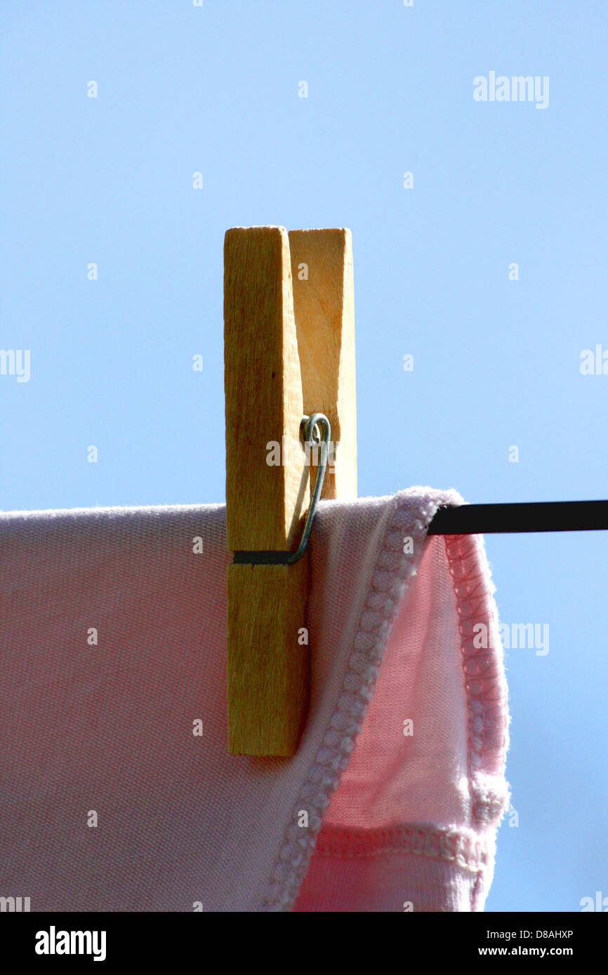 A wooden clothespin securely fastens laundry to a clothesline, as ...