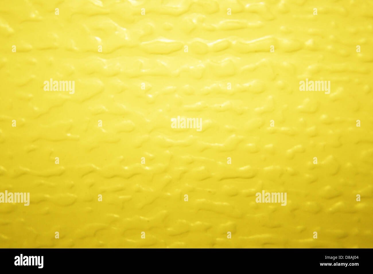A close-up of a yellow plastic surface with a bumpy texture. The ...