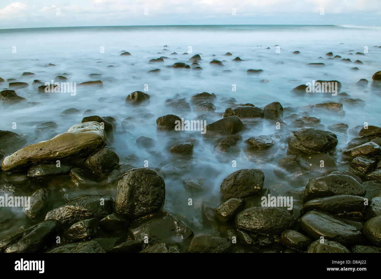 Long exposure photograph of the surf washing around the boulders at ...