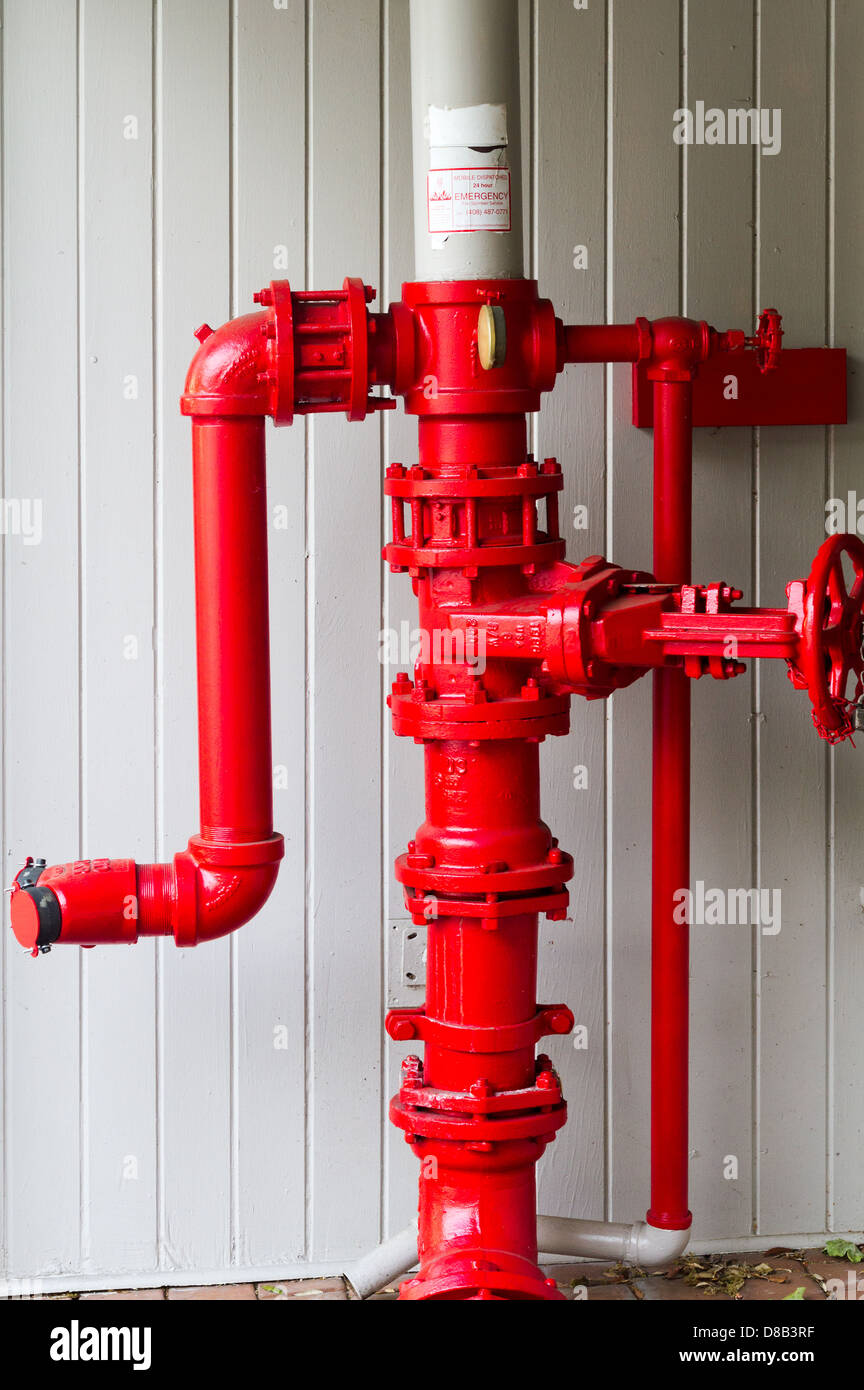 A network of pipes and valves are decoratively painted bright red ...