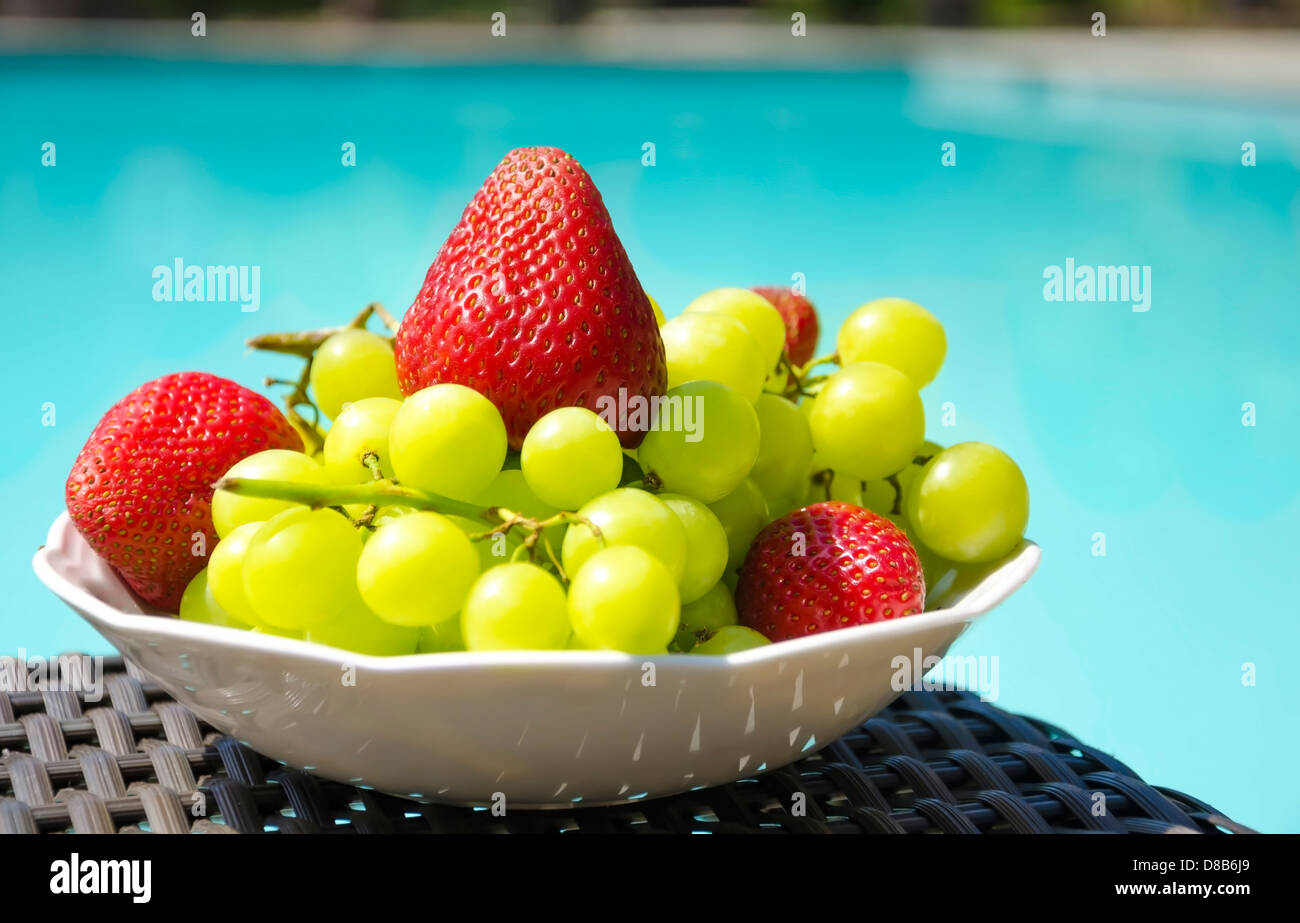 Strawberry and grape in white plate on table by the swimming pool Stock ...
