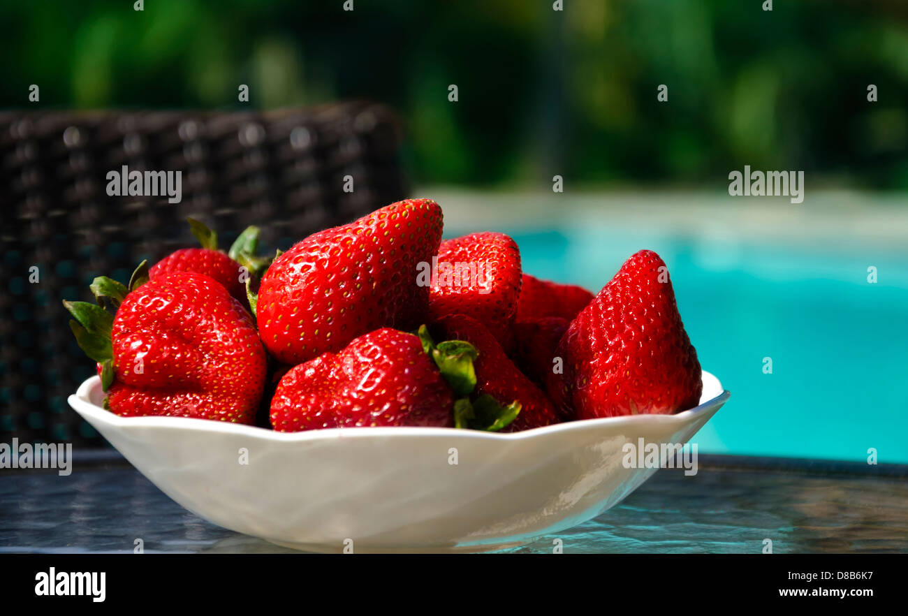 Strawberry in white plate on table by the swimming pool Stock Photo - Alamy