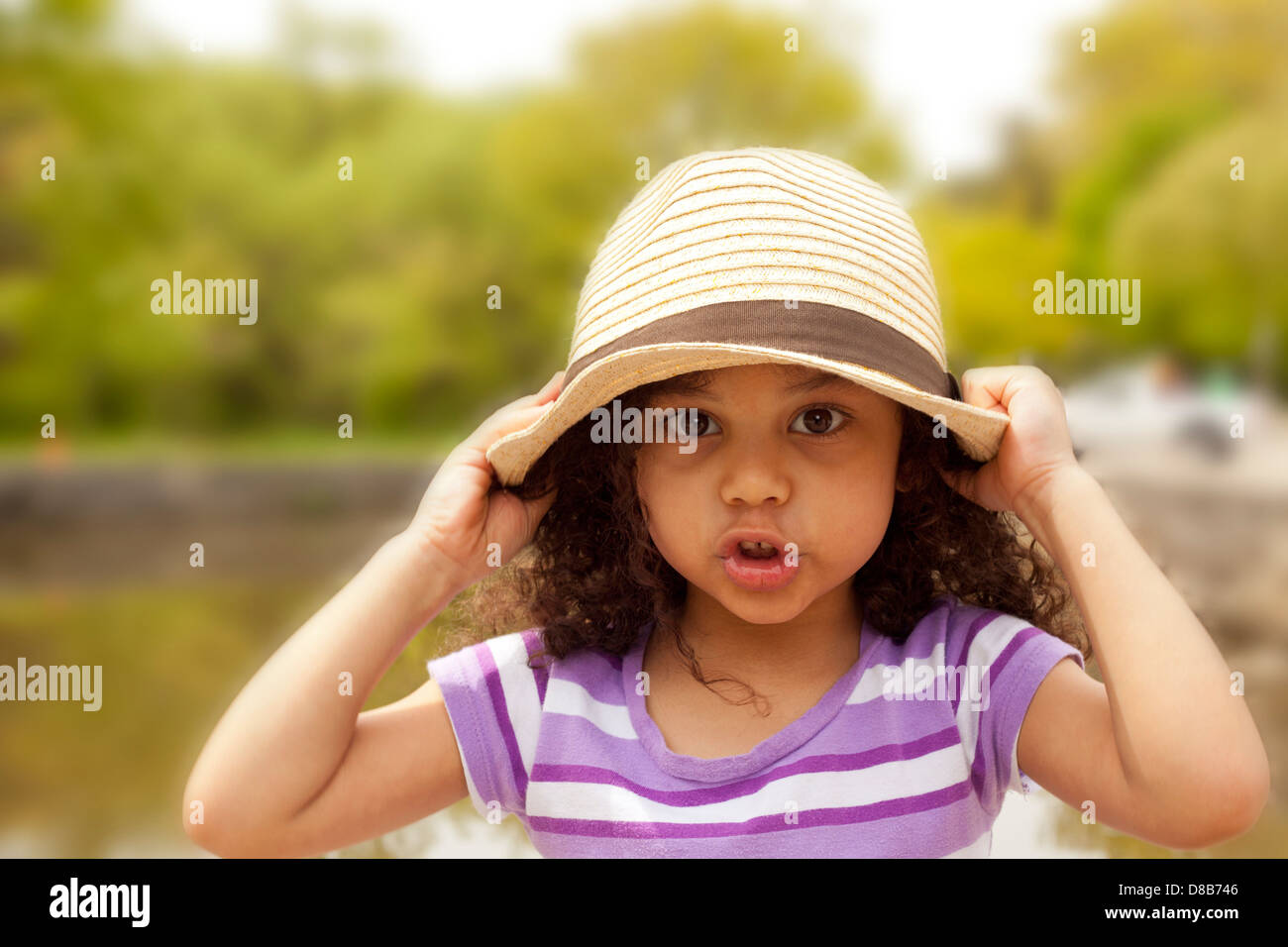 cute little ethnic girl pulling down her hat Stock Photo - Alamy