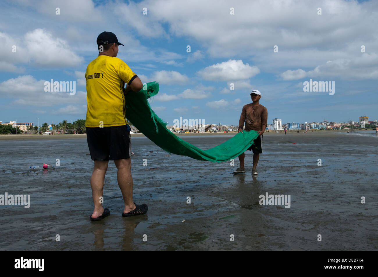 Two men from Manabi winding a fishing net on the beach of Tarqui Stock ...