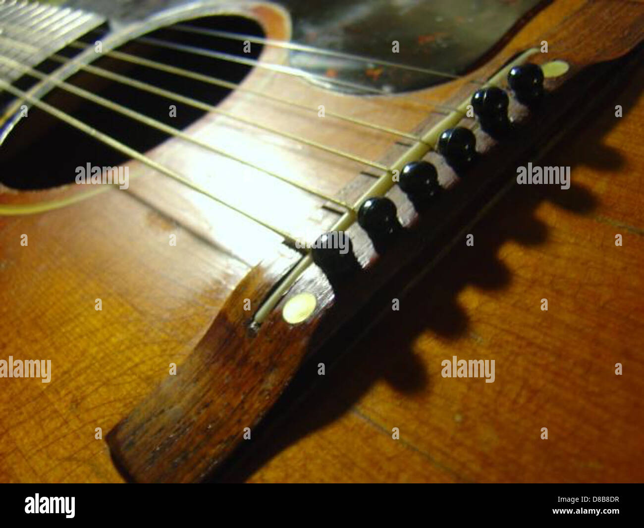 A close-up image of an acoustic guitar bridge, showing the fine ...