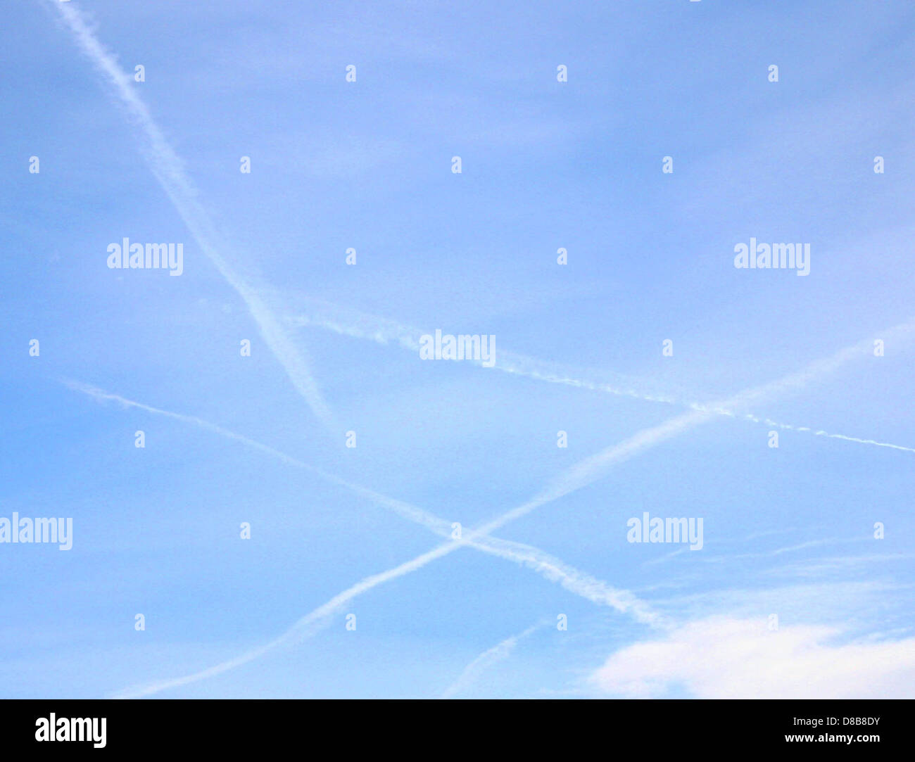 Airplane contrails streak across the blue sky, leaving behind thin ...