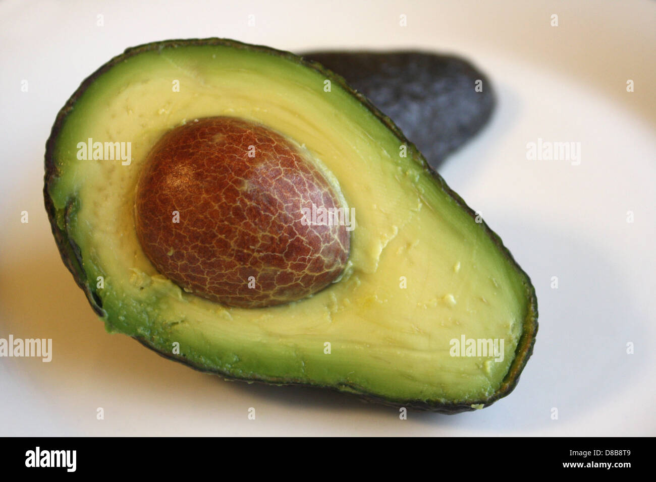 A close-up image of a ripe avocado cut in half, revealing its creamy ...