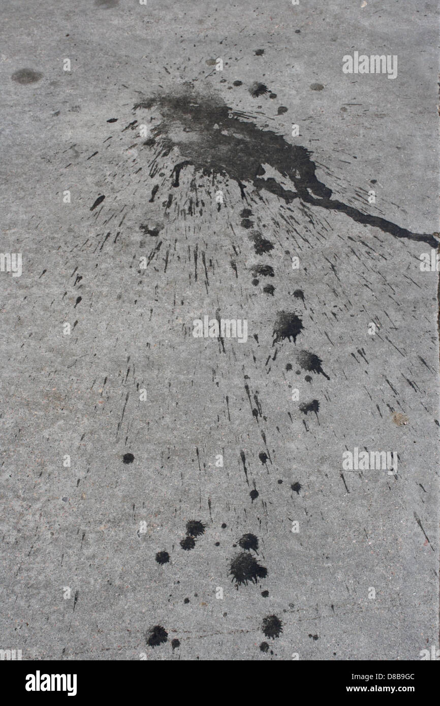 A close-up of black paint splatter on a cement sidewalk, illustrating ...